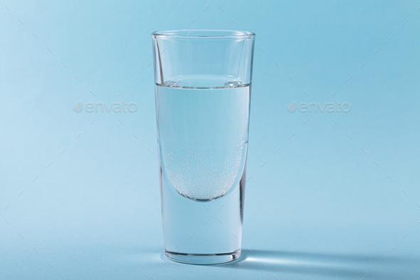 Glass of pure sparkling water on light blue background Stock Photo by svittlana
