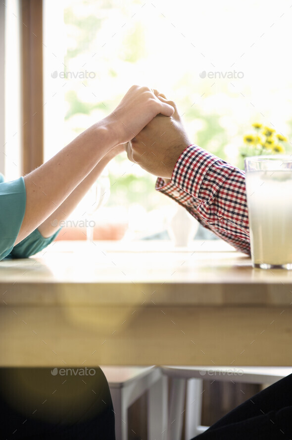 Cropped shot side view of couple holding hands across table Stock Photo ...