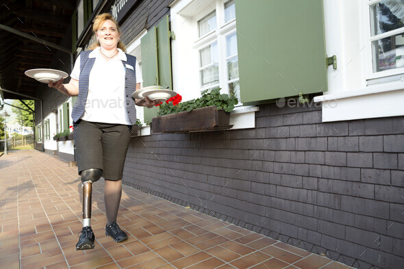 Mid adult woman with prosthetic leg, carrying plates, outdoors Stock ...