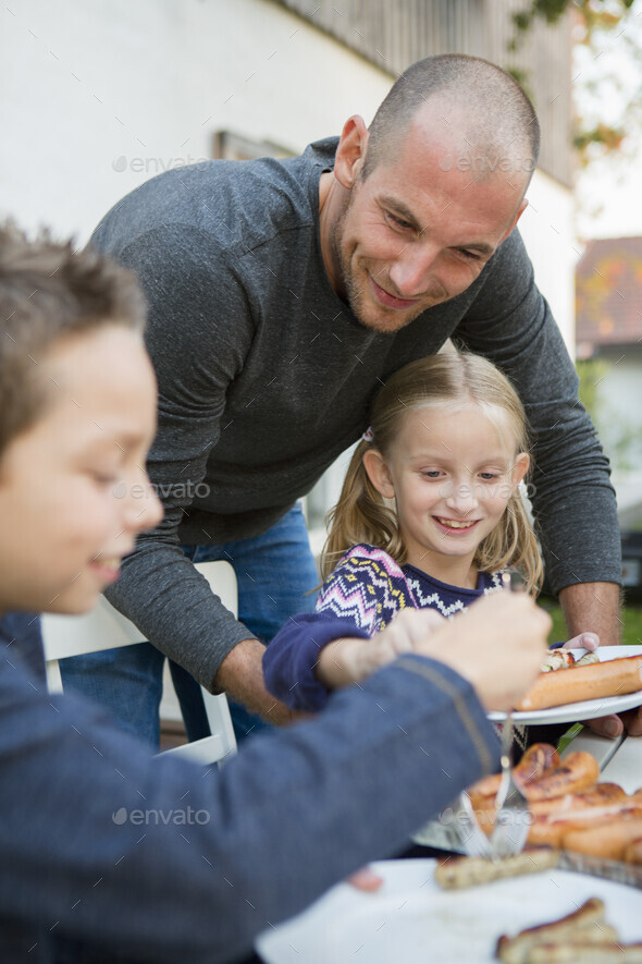 Father helping children at garden barbecue table Stock Photo by Image ...