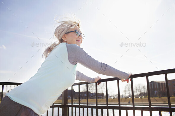 Side view of woman leaning against railing looking away Stock Photo by ...