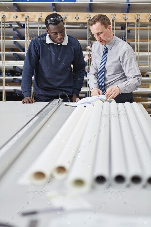 Manager and factory worker checking paperwork in roller blind factory ...