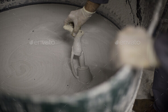 Artist dipping object into vat of plaster of paris Stock Photo by Image ...