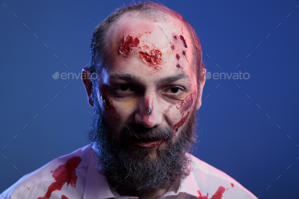 Man dressed as evil undead ghoul, wearing fake wounds makeup, studio ...
