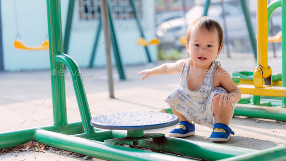 Portrait of smiling Asian boy squatting and playing with rotating plate ...