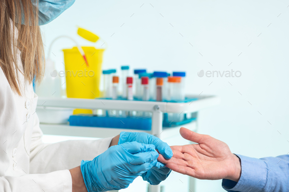 Nurse draws blood sample from patient's finger with finger prick method ...