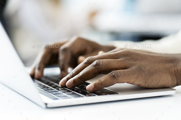African American programmer writing code on laptop keyboard at ...