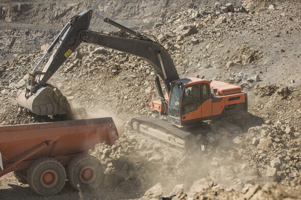 Excavator loading rocks into a dump truck at a quarry. Stock Photo by ...
