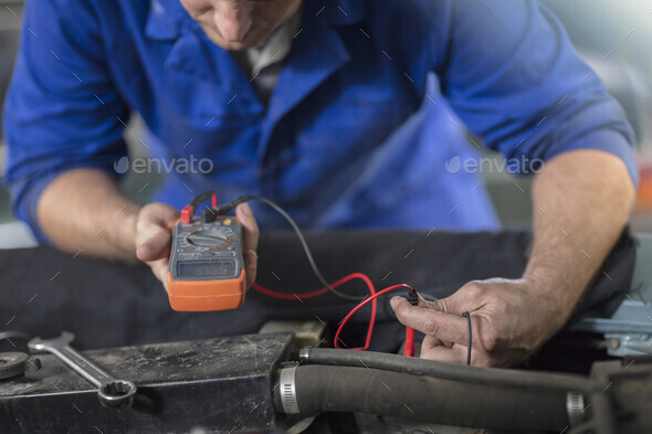 Mechanic using a multimeter on a vehicle. Stock Photo by Image-Source