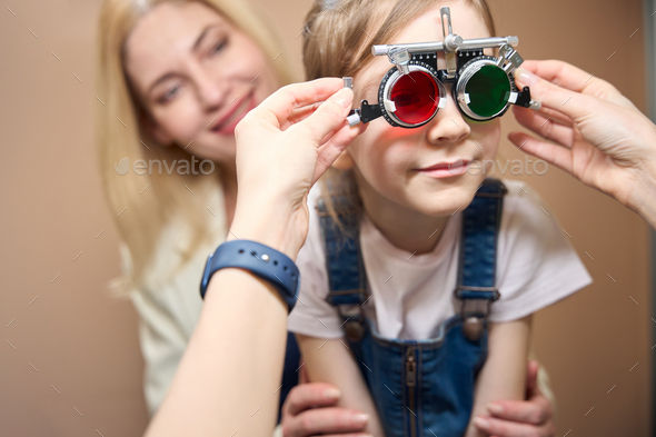 Specialist ophthalmologist checks a child eyes using a special gadget ...