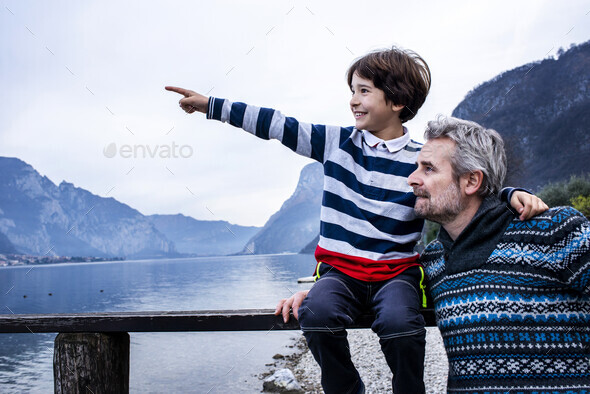 Boy and father pointing from lakeside pier, Lake Como, Onno, Lombardy ...