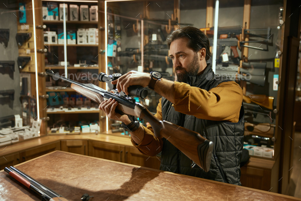 Salesman demonstrating professional accuracy gun assembly at counter ...