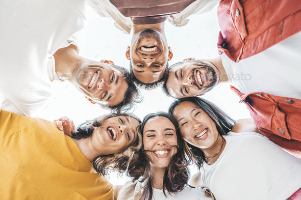 Multicultural young people hugging together and smiling at camera Stock ...