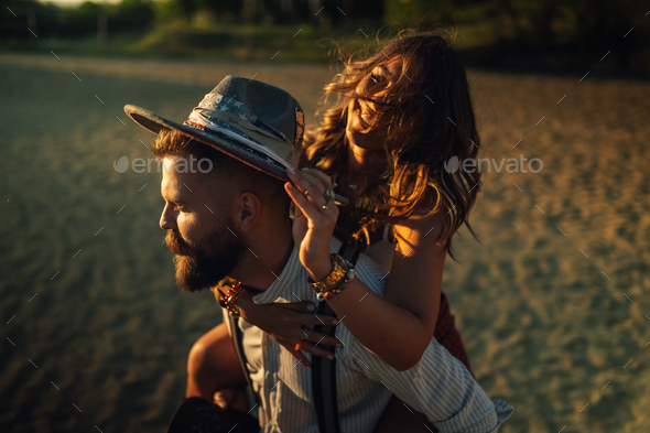 Portrait of cowgirl and cowboy having piggyback ride at ranch at sunset ...