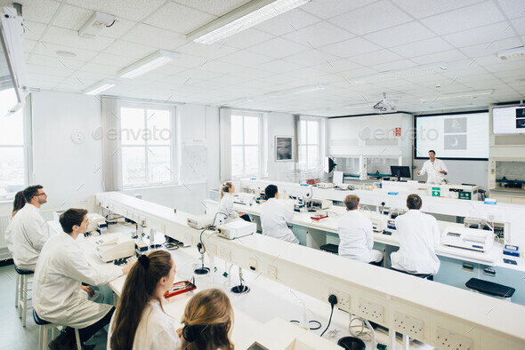 Students engaged in a science lab class with a teacher overseeing the ...