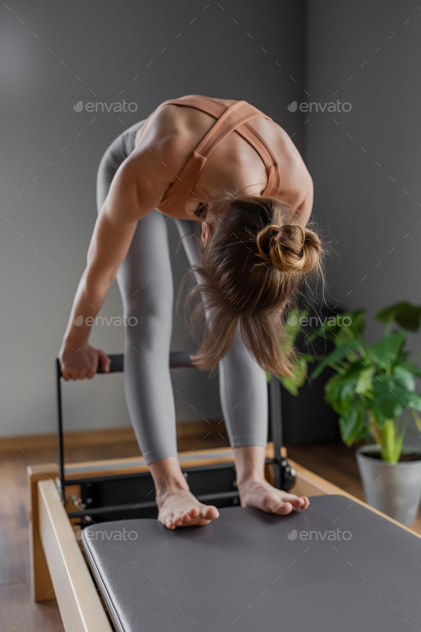 Woman doing Pilates exercise for core and back muscles on Reformer ...