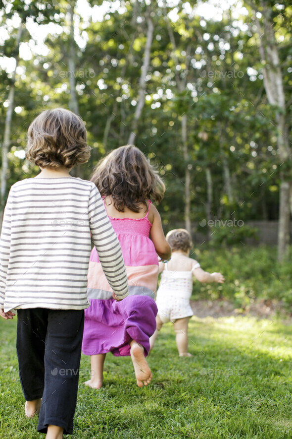 Three children playing in a sunny backyard, exploring nature together ...