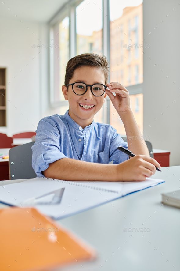 The studious scholar: a boy with glasses at the classroom table Stock ...