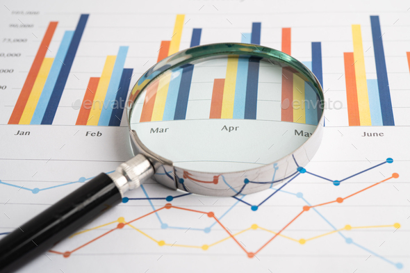 Magnifying glass on spreadsheet and graph paper. Financial development ...