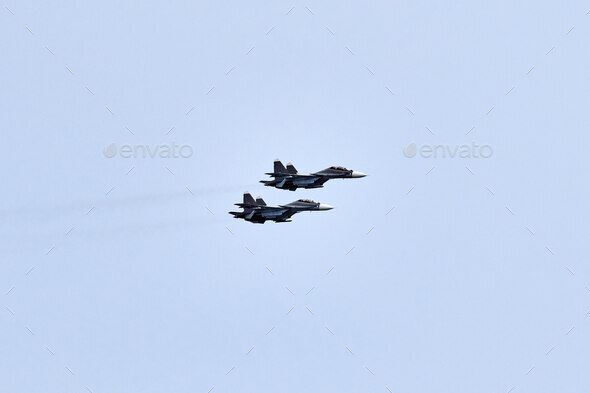 Two Russian military fighter planes armed with missiles flies in blue ...