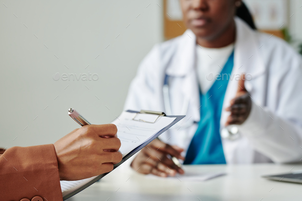Patient making notes in medical document Stock Photo by Pressmaster