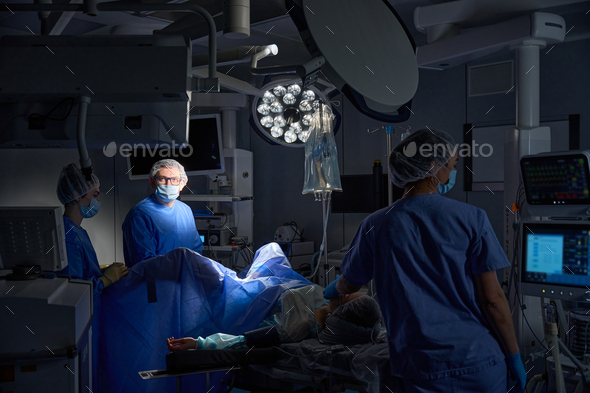 Group of surgeons in operating room with surgical laparoscopy equipment ...