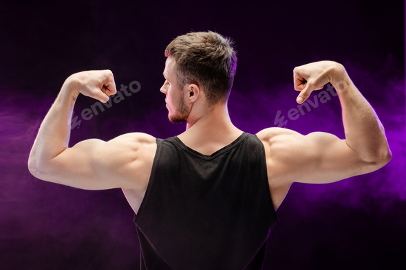 Bodybuilder showing muscles posing on purple background Stock Photo by ...