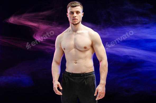 Handsome bodybuilder posing showing his muscles on dark background with ...