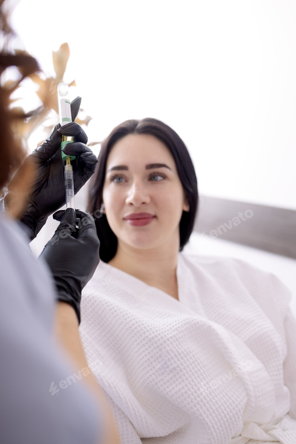 doctor holding injector performing mesotherapy of patient woman's face ...