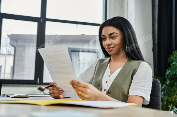 Focused African American Woman Reviewing Documents in Modern Workspace ...