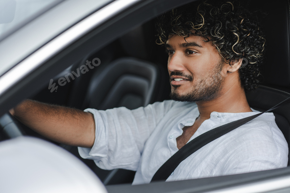 Smiling handsome Indian man driving car smiling and looking away Stock ...