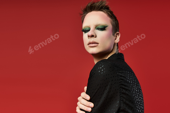 Young Drag Artist in Vibrant Attire Posing Against Bold Red Background ...