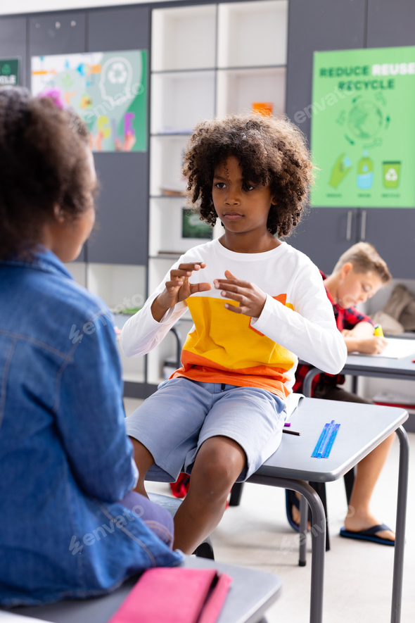 Happy diverse schoolchildren using sign language in school classroom ...