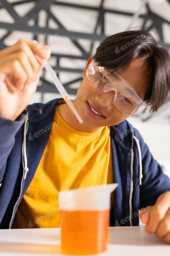 Conducting science experiment, teenager using pipette and beaker in ...