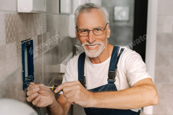 Electrician smiling installing a power outlet in a bathroom Stock Photo ...