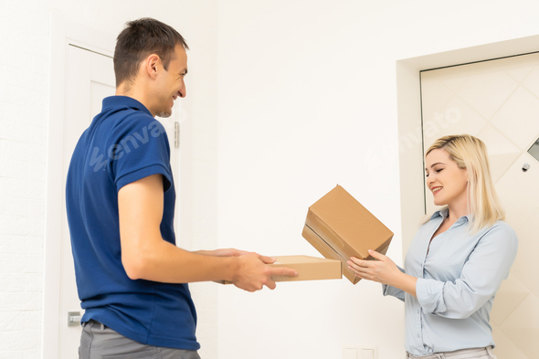 woman receiving boxes from postman at the door in home delivery concept ...