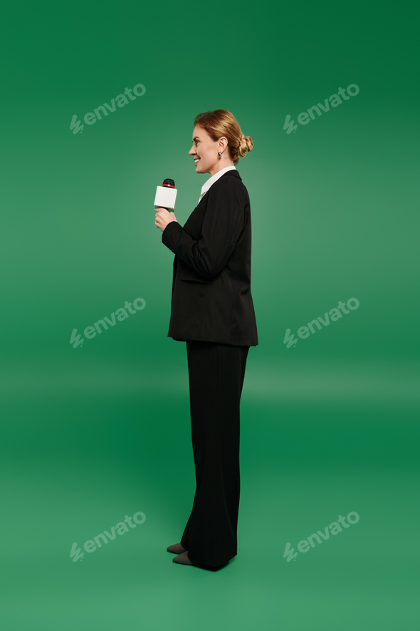 Elegant TV presenter in black formal attire in a bright green setting ...