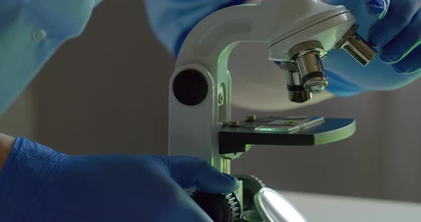 Close-up Shooting. A Lab Worker Is Looking Into a Microscope and ...