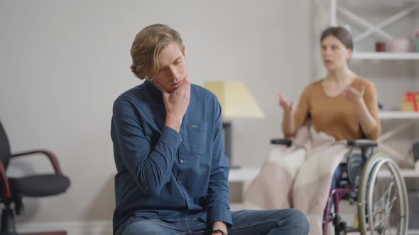 Overwhelmed Caucasian Young Man with Blurred Angry Disabled Woman in ...