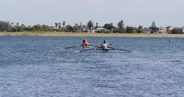 Four senior caucasian men and women in rowing boat raising hands and ...