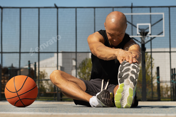 Basketball player stretching legs after game. Outdoors training ...