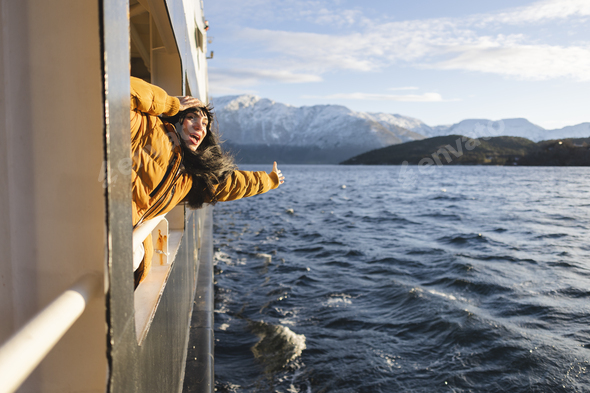 Excited woman leans out of a ferry, enjoying the fresh air and ...