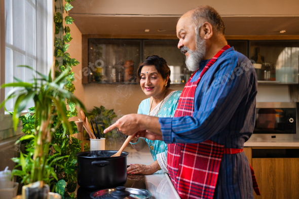 Senior Indian couple bonding over cooking, enjoying retirement life in ...