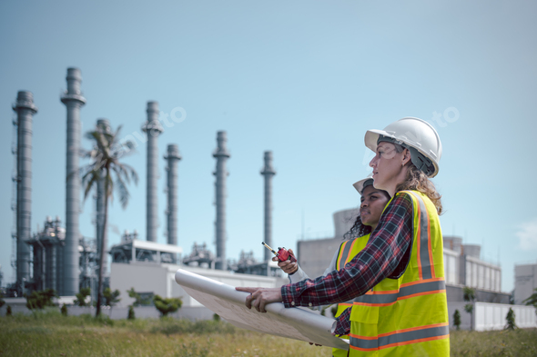 Engineers wearing safety gear, including hard hats examining survey a ...