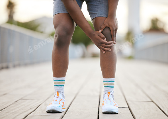 A man grabbing his knee in pain from exercising. An African American ...