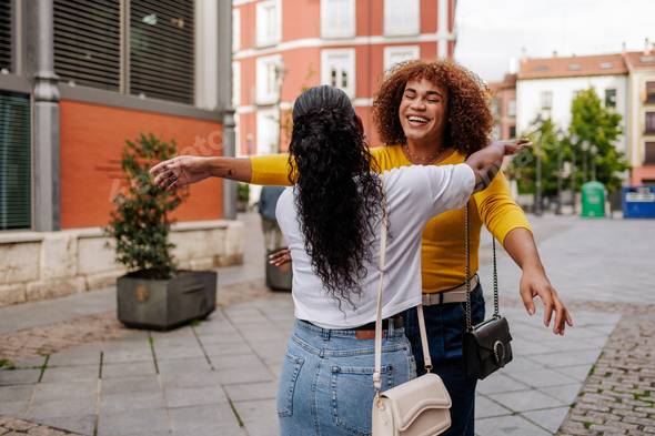 Transgender woman hugging her friend in city street. Friends meeting ...