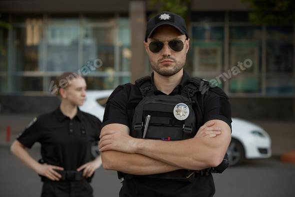 Serious brave man patrol police officer with policewoman on background ...