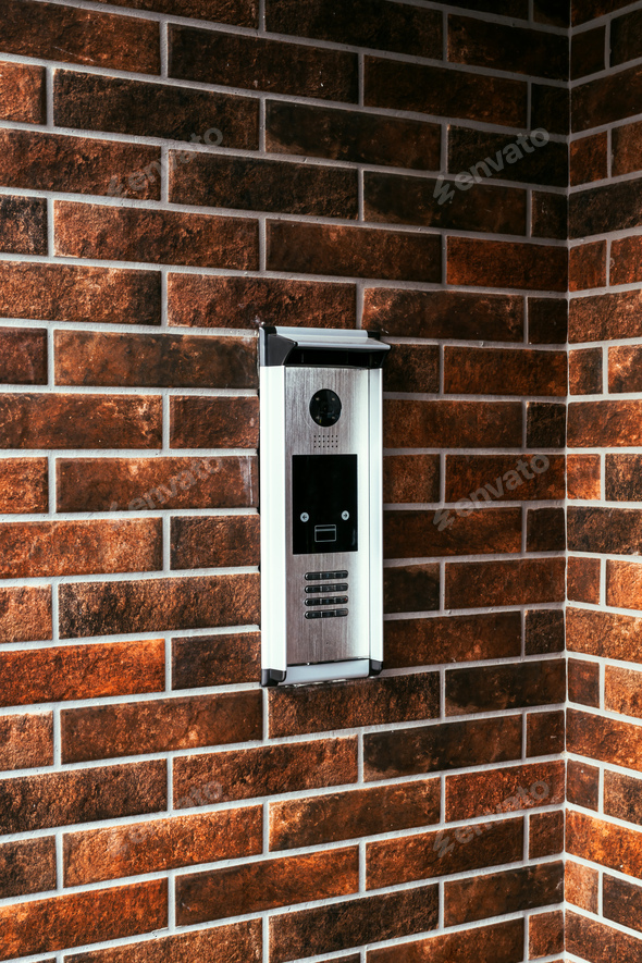 Modern intercom device at residential building entrance door with camera and dial keypad lock ...