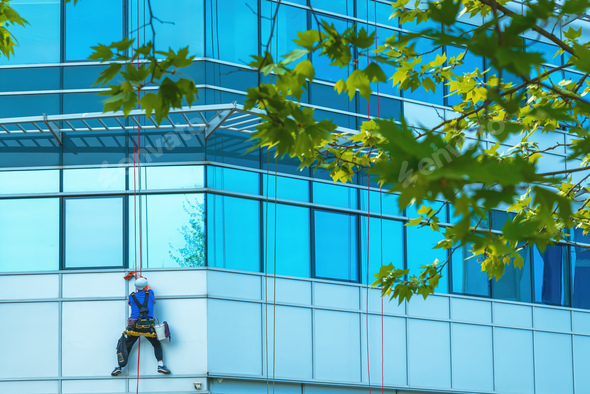 Window washer cleaning facade of modern office building Stock Photo by ...