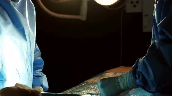 Mid section of surgeons performing operation in operation room, Stock ...